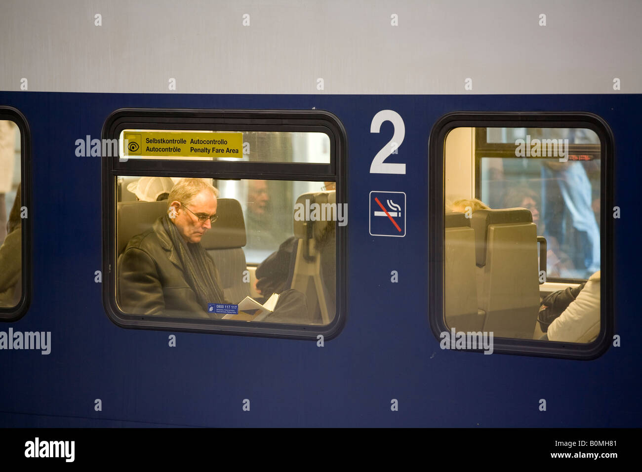 Man reading paper in Swiss train Stock Photo - Alamy