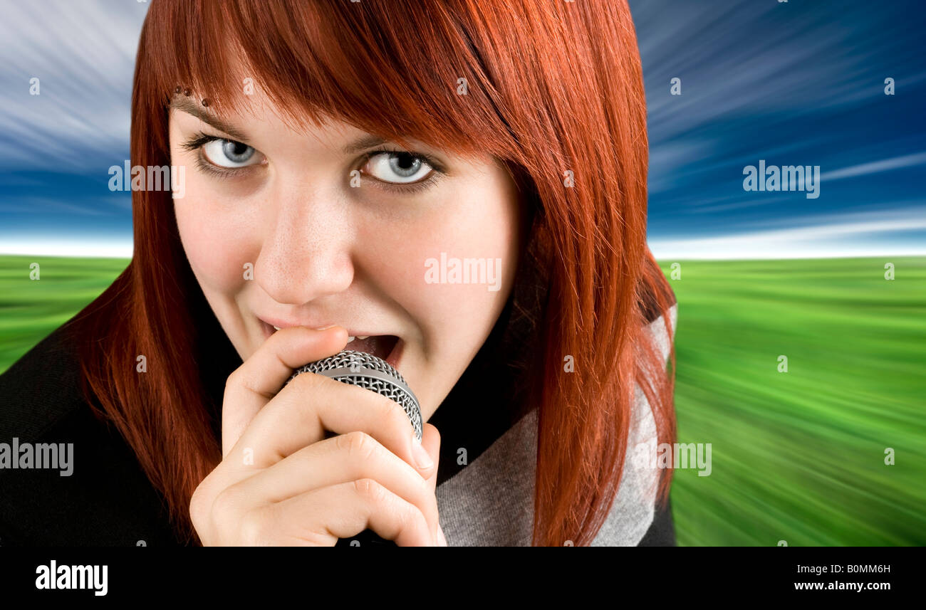 Happy redhead girl singing karaoke on a microphone Studio shot Stock ...