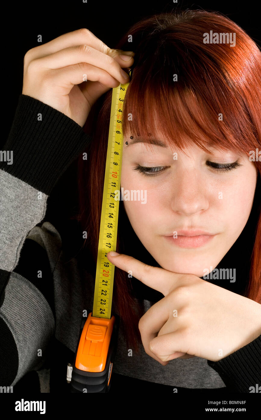Redhead girl pointing finger at a measuring ruler tool Studio shot ...