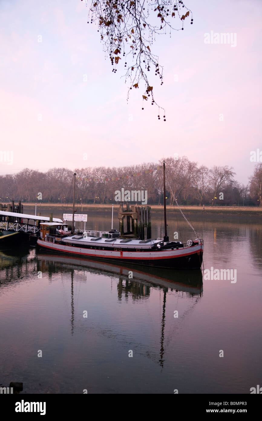 View of masted boat moored to a jetty, on the Thames at Putney. London ...