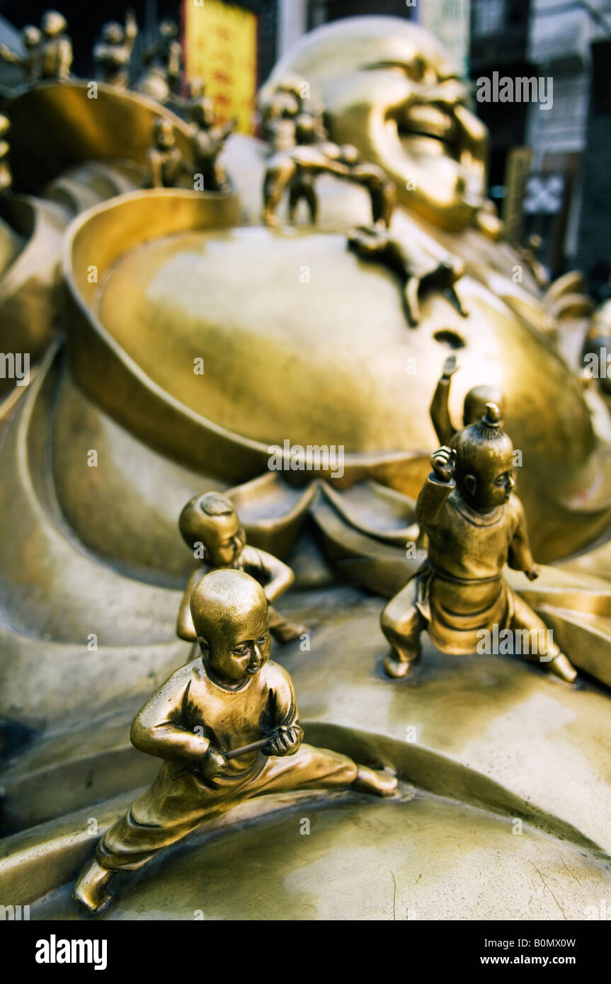 a golden statue of a reclining laughing buddha covered in small buddhas ...