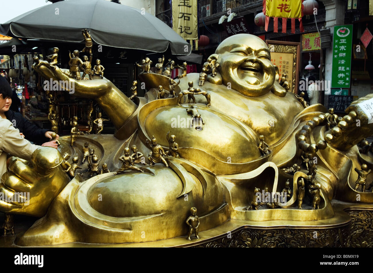 a golden statue of a reclining laughing buddha covered in small buddhas ...