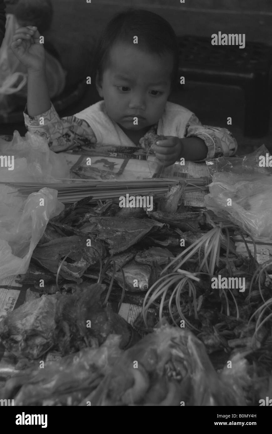 little kid playing whilst mother sells fish at market Stock Photo - Alamy