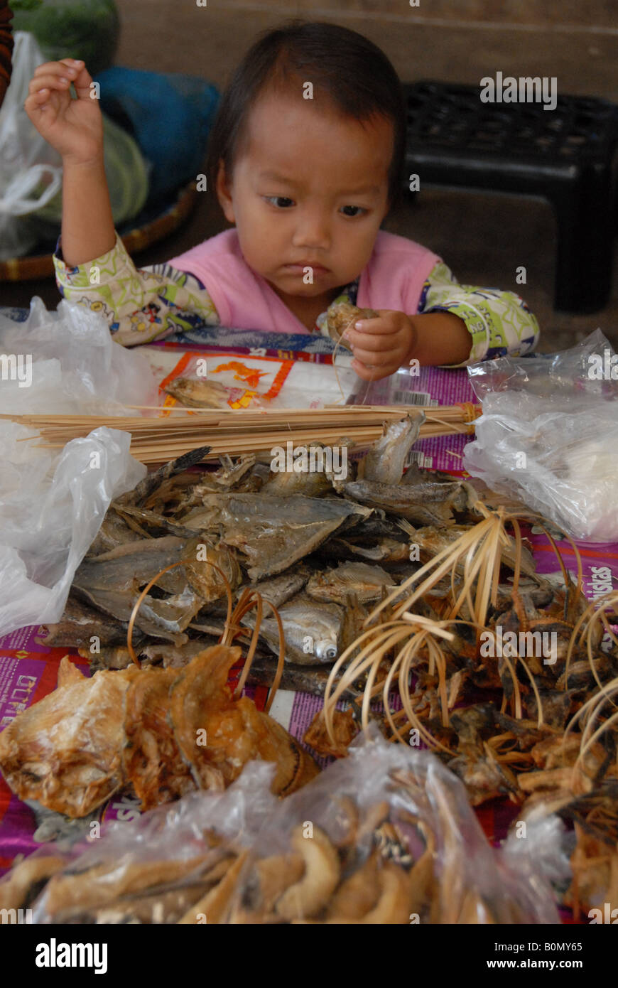 little kid playing whilst mother sells fish at market Stock Photo - Alamy