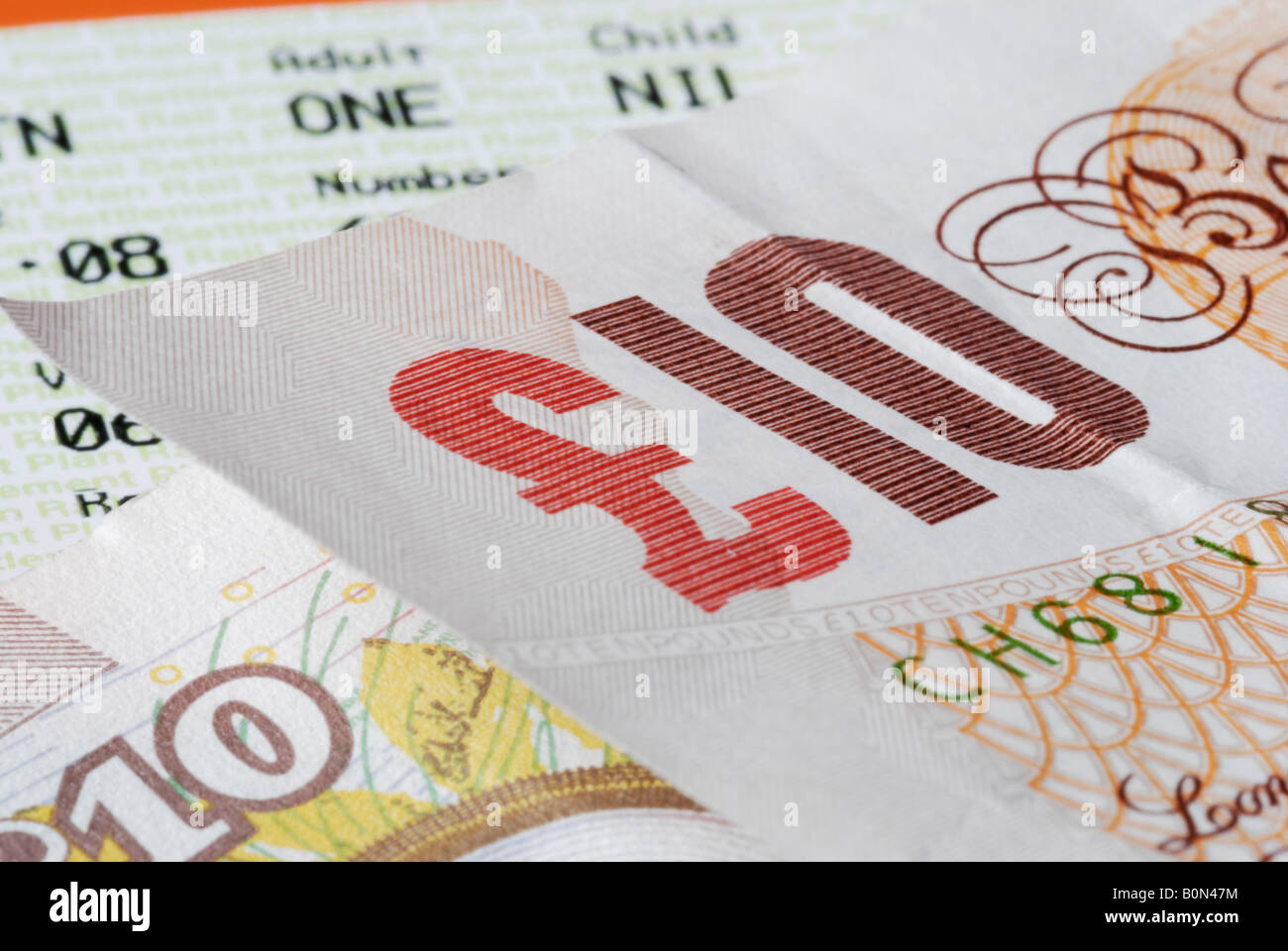 Close up of UK ten pound notes with train ticket in the background ...