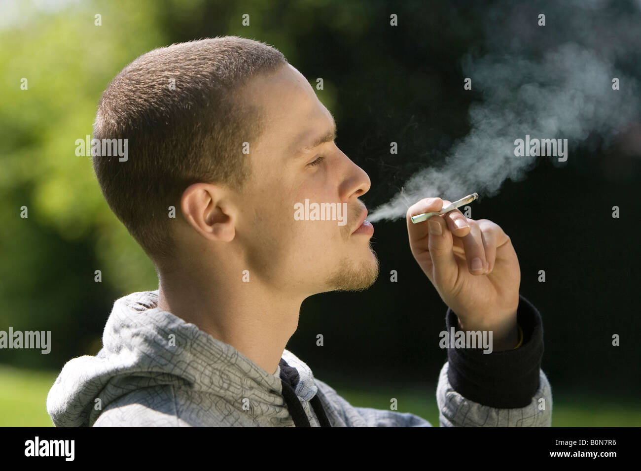 young man smoking roll up cigarette outside that looks like a joint ...