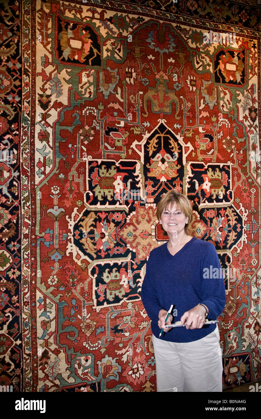 Portrait of female salesperson with antique rug hanging in store ...