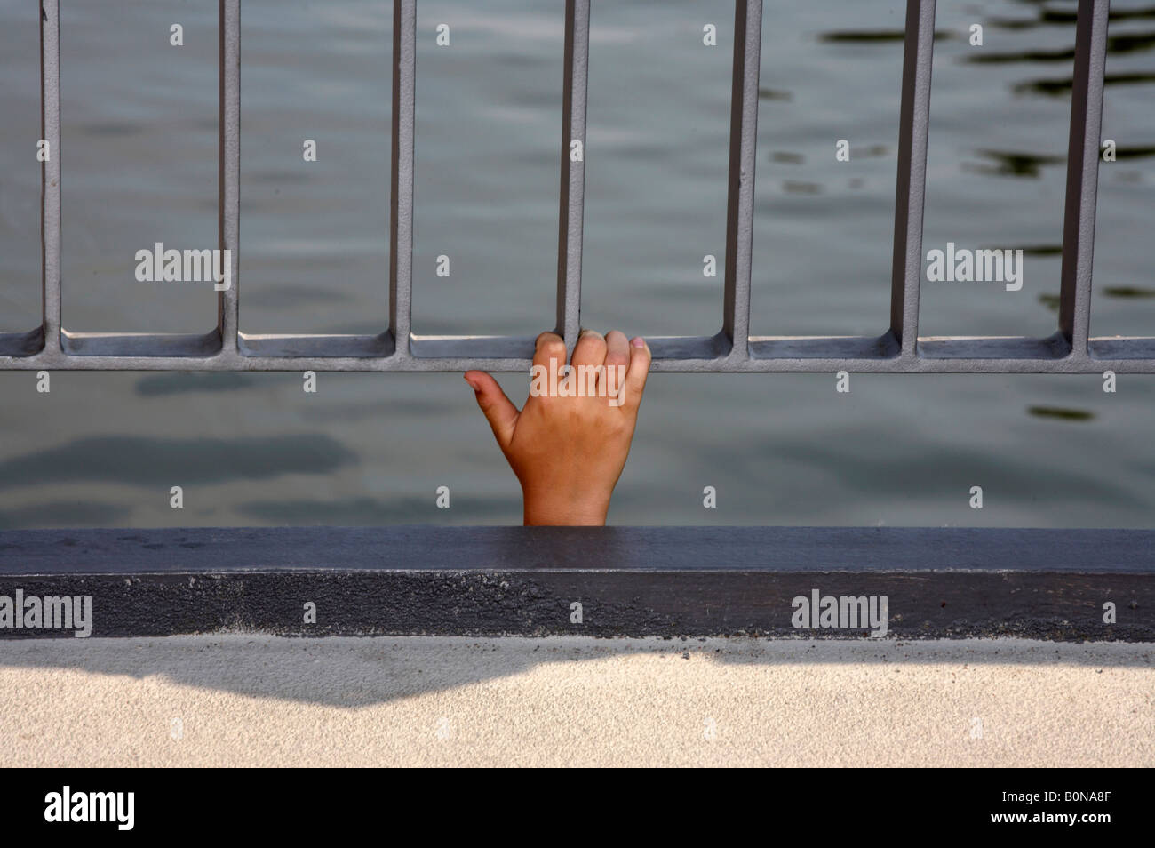 Hand of boy holding onto a rail above a river Stock Photo - Alamy