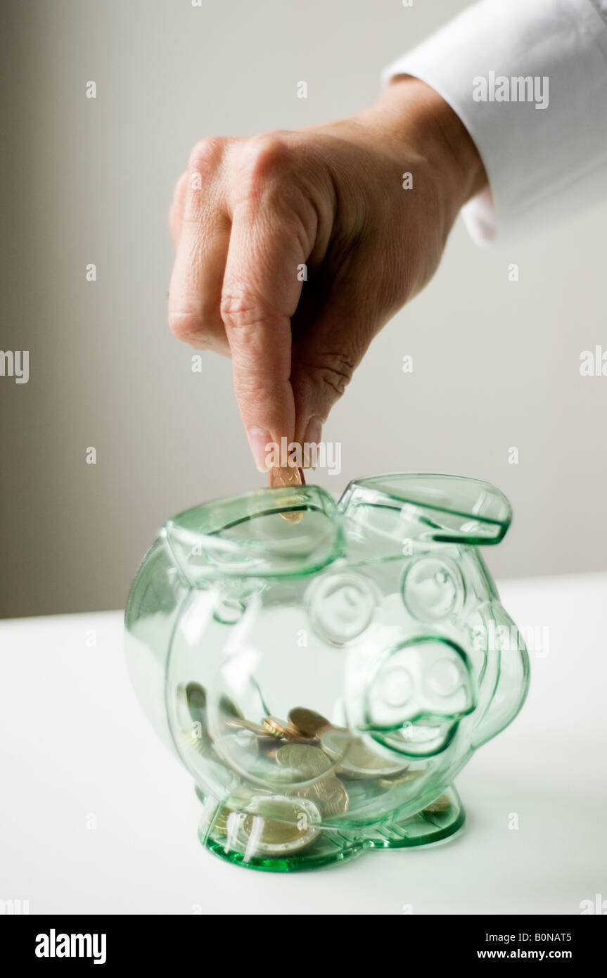 Hand dropping coins into a piggy bank hi-res stock photography and ...