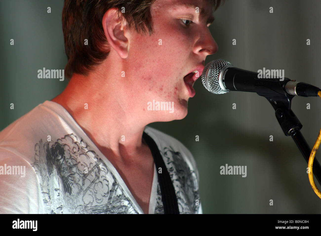 Underlit slightly spotty teenager sings into a microphone Stock Photo ...