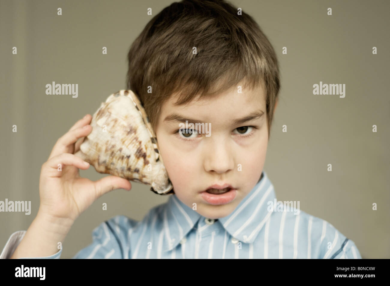 Boy holds seashells to his ear Stock Photo - Alamy