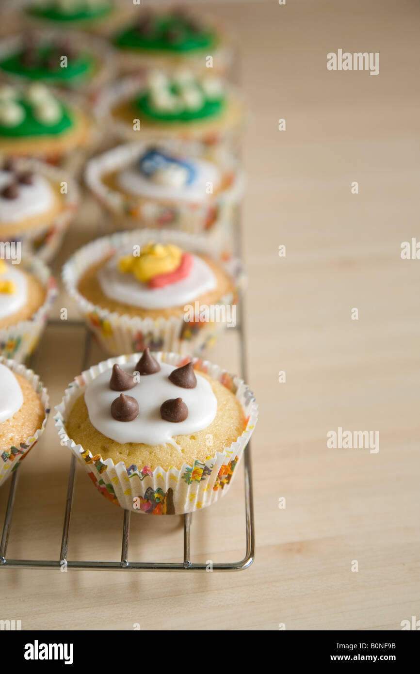 Colourful iced cupcakes on a wire rack on a kitchen worktop Stock Photo ...