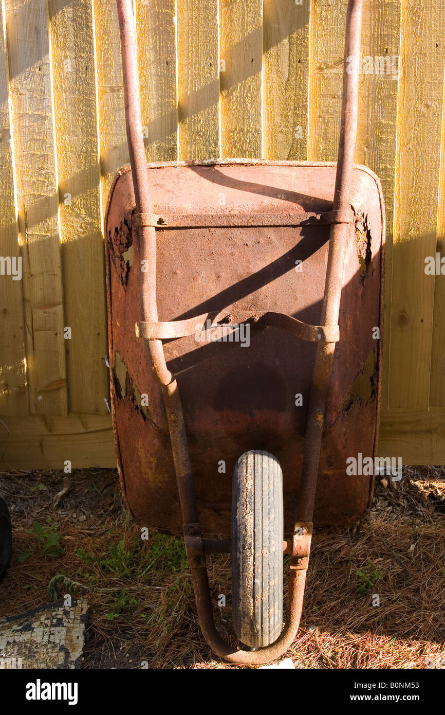 Old rusty wheelbarrow propped against fence Sandbanks Dorset UK Stock ...