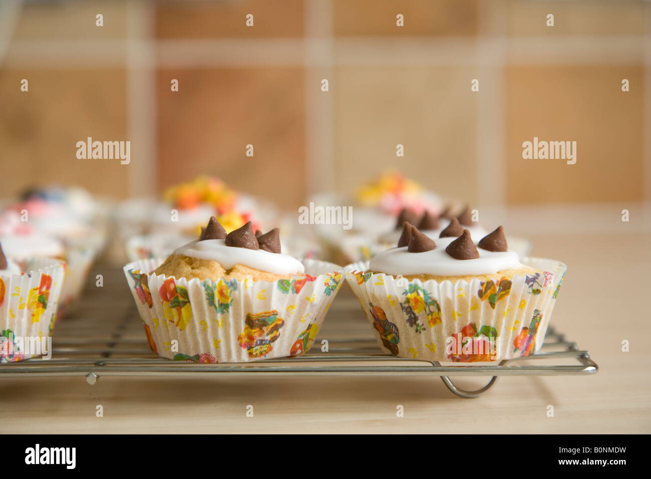Colourful iced cupcakes on a wire rack on a kitchen worktop Stock Photo ...