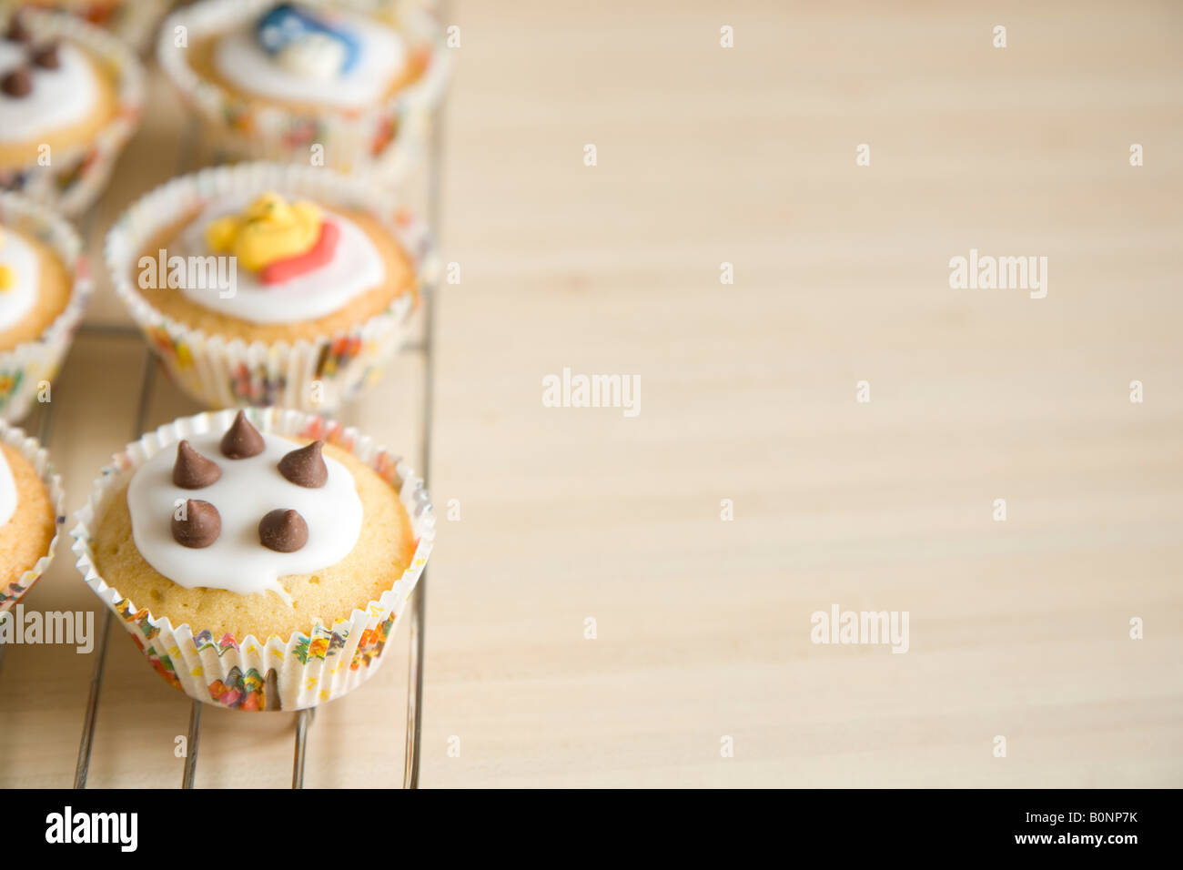 Colourful iced cupcakes on a wire rack on a kitchen worktop Stock Photo ...