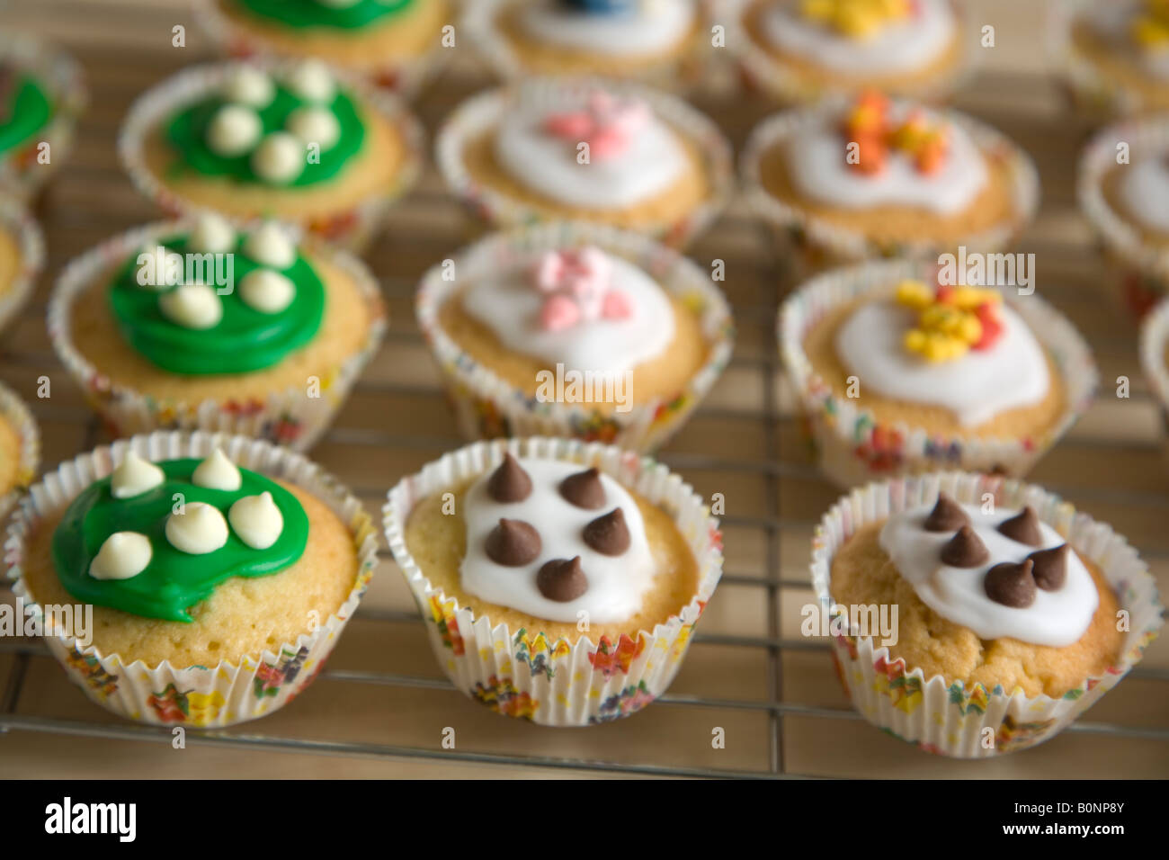 Colourful iced cupcakes on a wire rack on a kitchen worktop Stock Photo ...