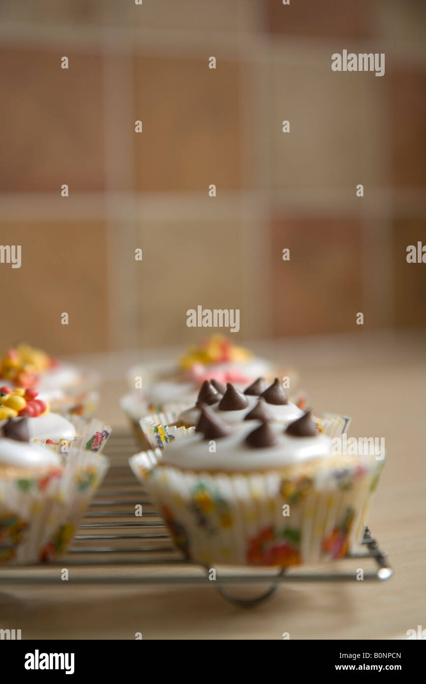 Colourful iced cupcakes on a wire rack on a kitchen worktop Stock Photo ...