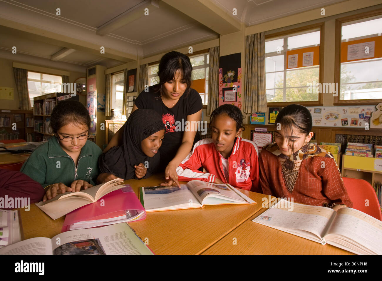 Female teacher explaining to students in a classroom Stock Photo - Alamy