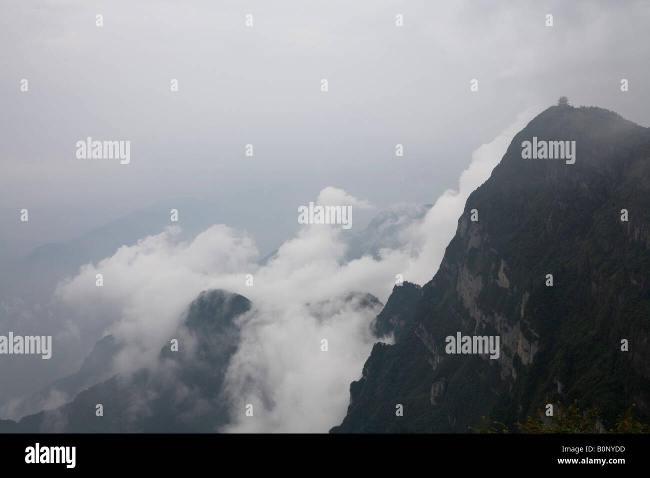 Cliff with remote Buddhist temple surrounded by clouds and mist Stock ...