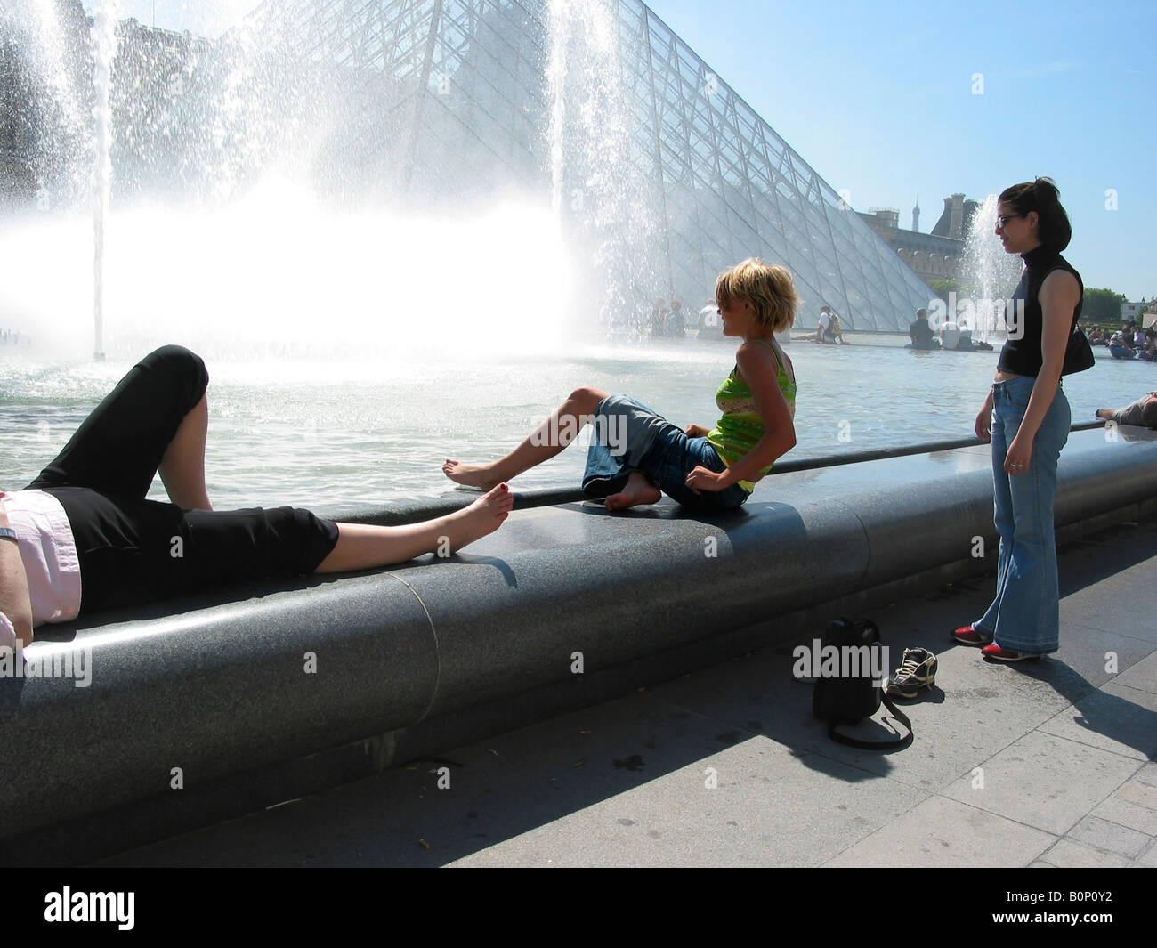teenage girls cooling off by pond at Louvre Pyramid Paris France Stock ...