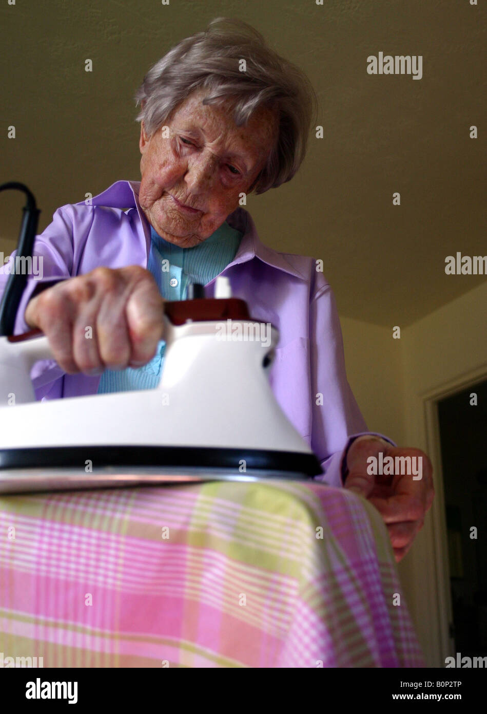 elderly woman ironing her clothes at home, ninety years old ...