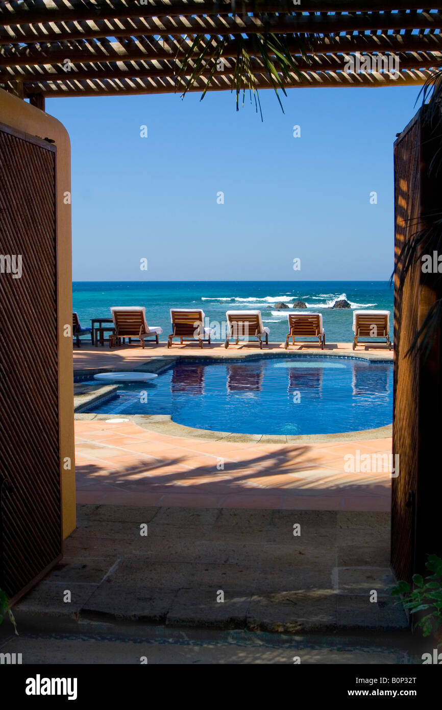 A view of a pool with chairs looking over a tropical ocean Stock Photo ...