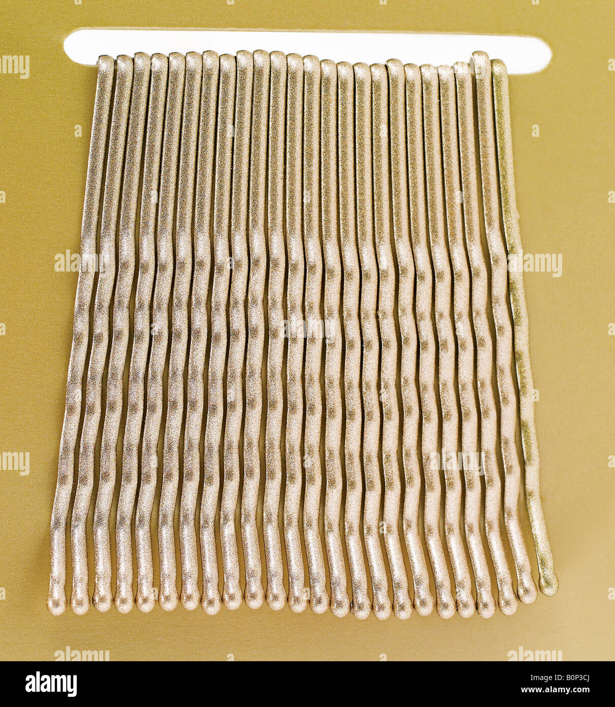 Row of Gold Bobby pins hanging on gold background Stock Photo - Alamy