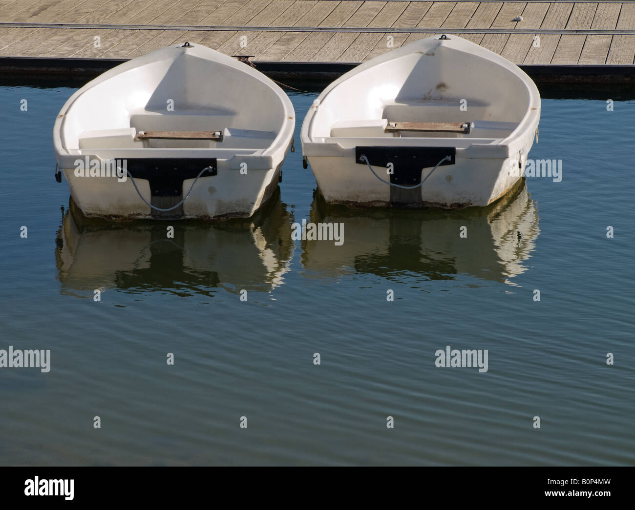 Two white, empty boats float on the clear, blue water Stock Photo - Alamy