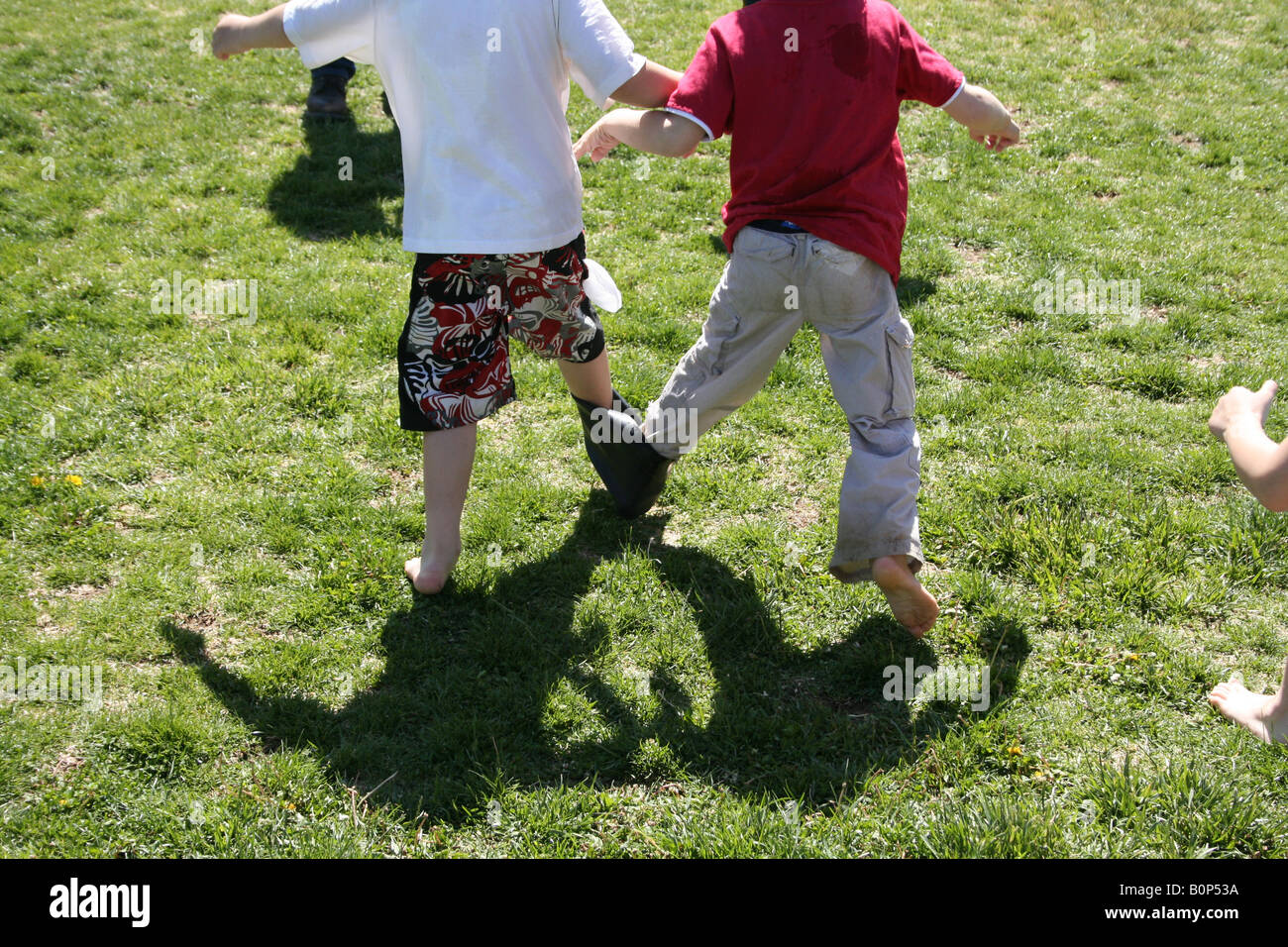 two kindergarteners racing together in a three legged race, feet ...