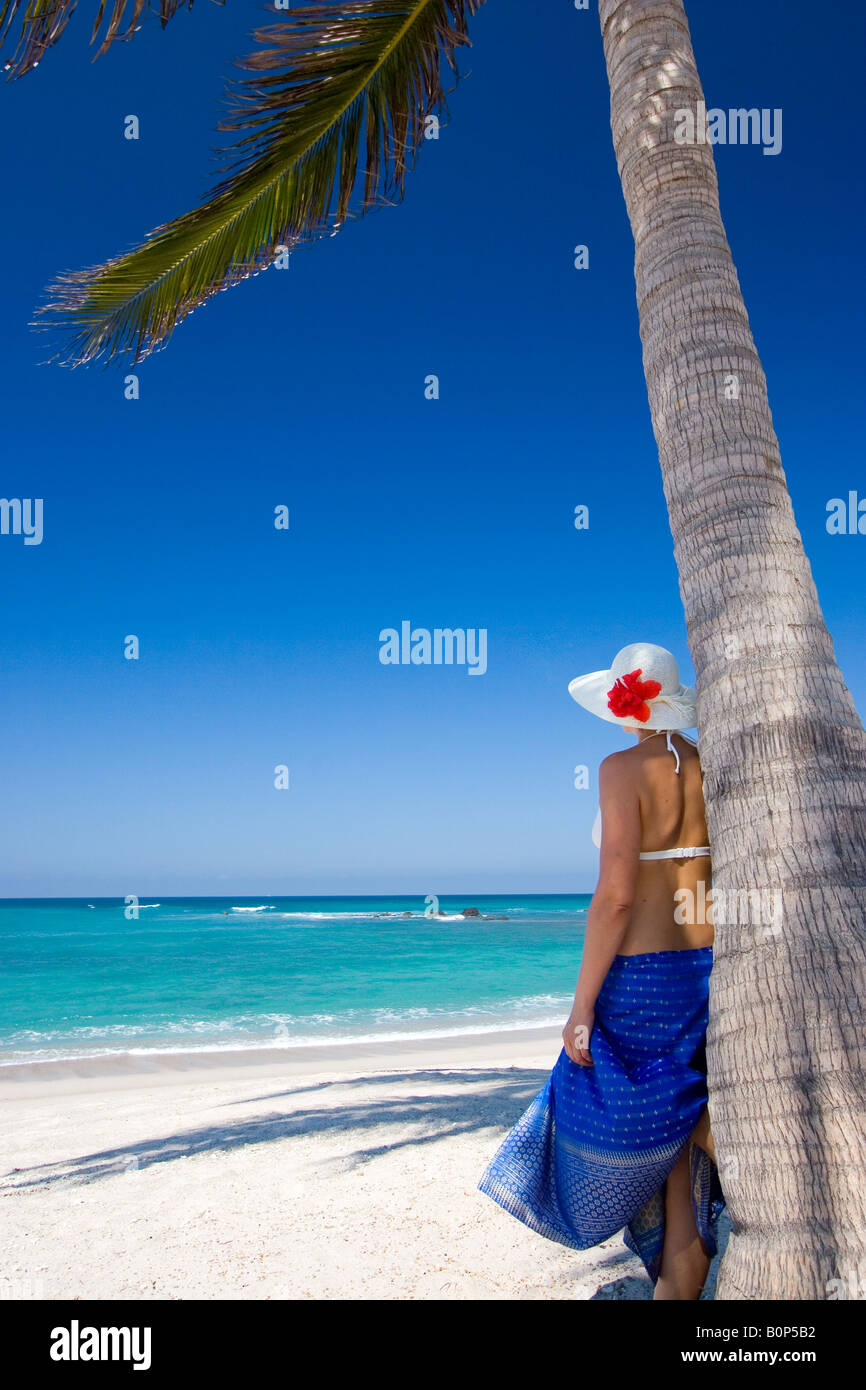 Woman standing against tree on tropical beach Stock Photo - Alamy