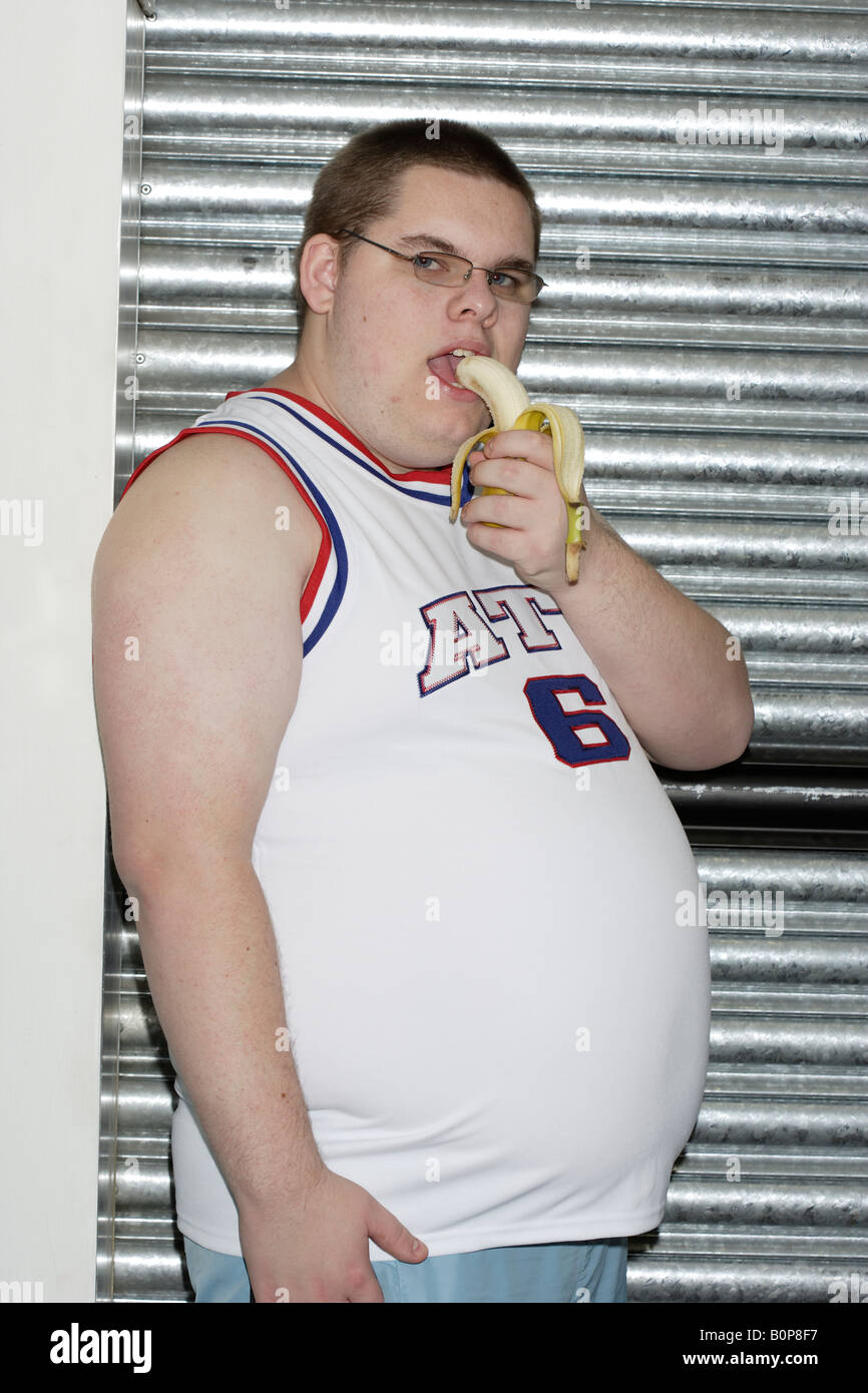 Large man in sports vest eating a banana Stock Photo - Alamy