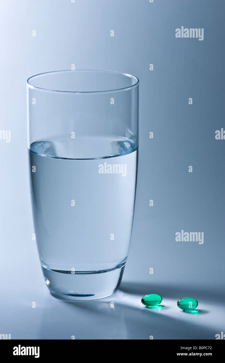 Light passing through a glass of water lighting two green tablets Stock ...