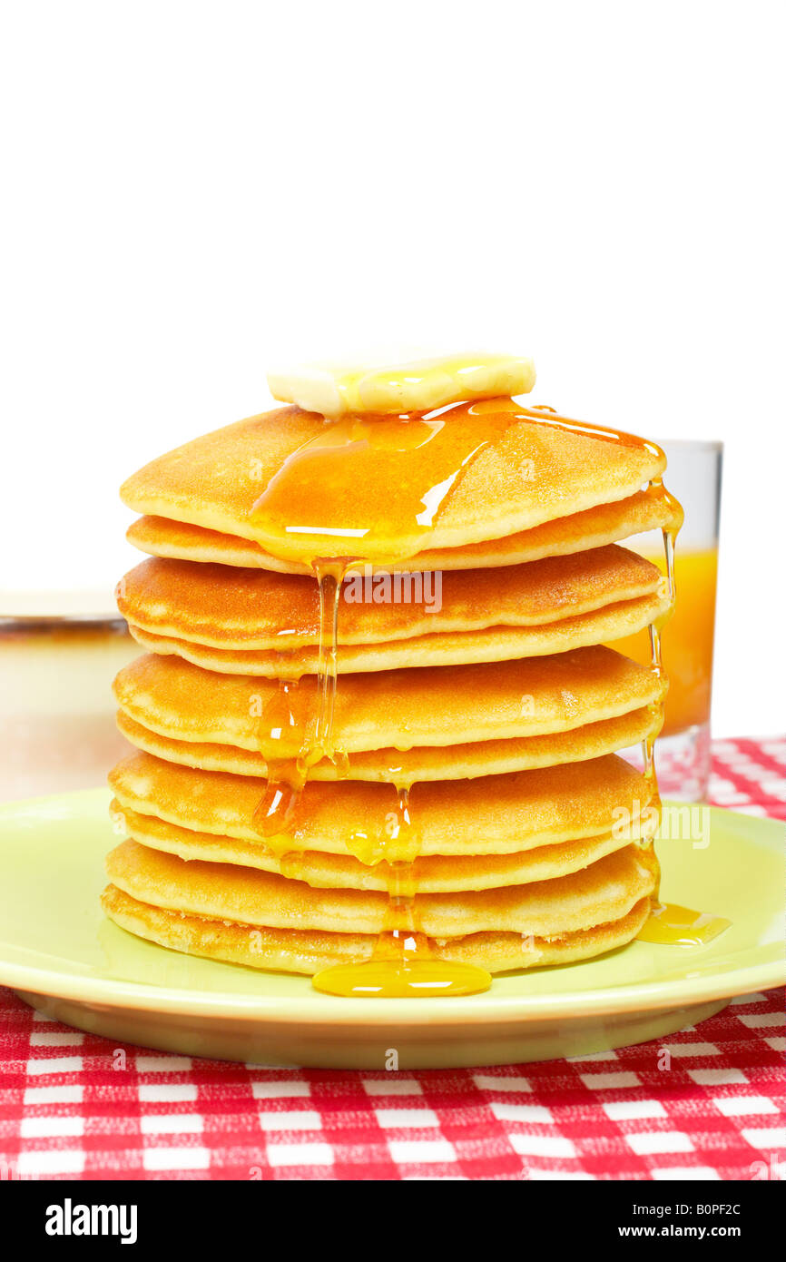 A big stack of pancakes with butter and orange juice on square ...