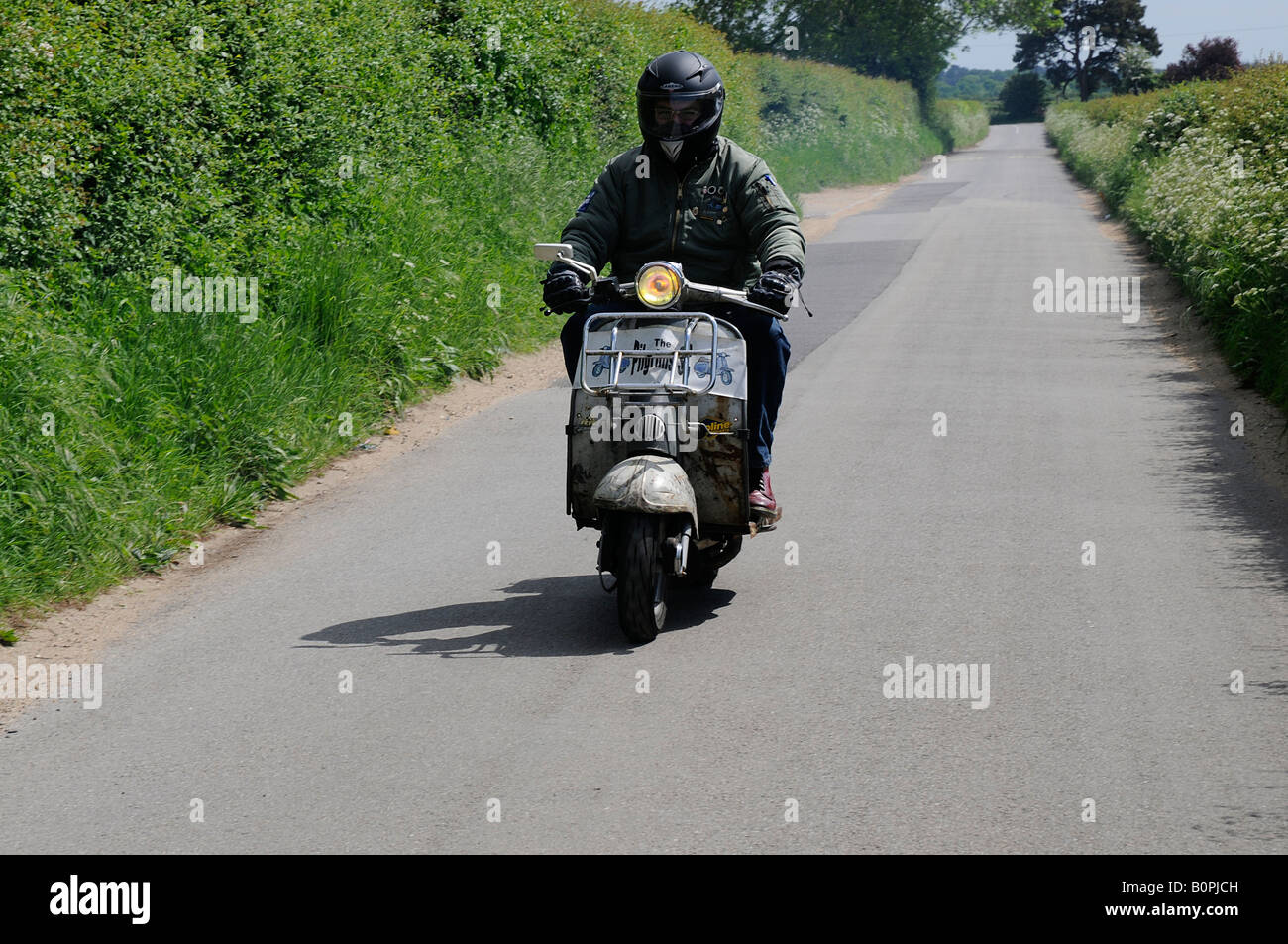 Scooterist riding along a country road Stock Photo - Alamy