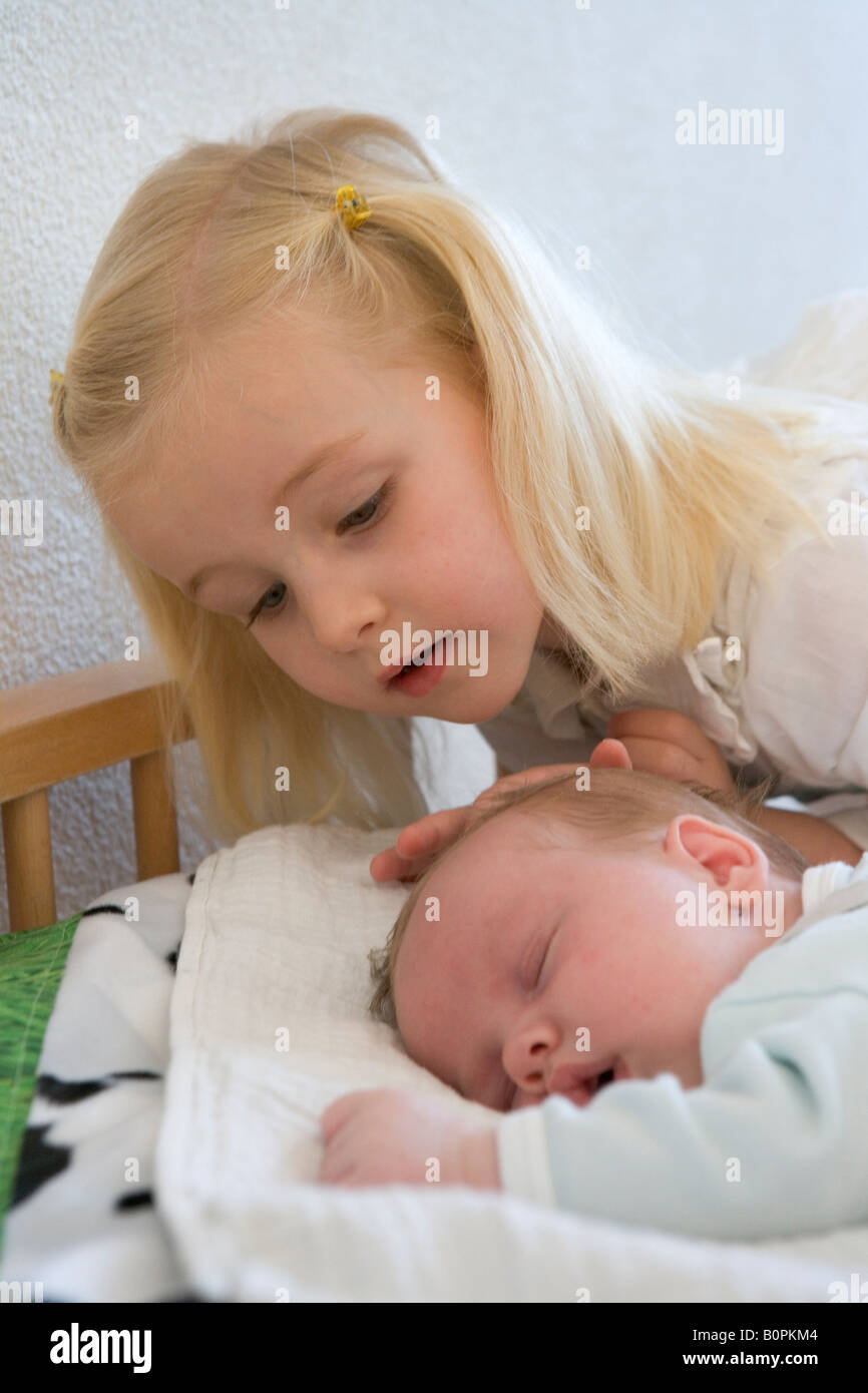 Little girl is touching the new baby Stock Photo - Alamy