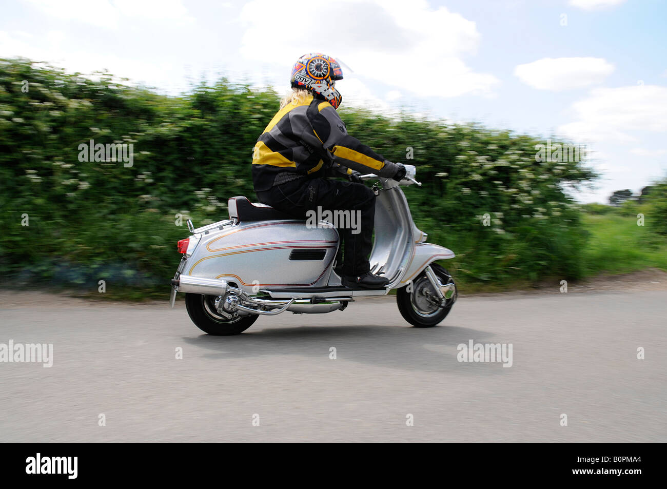 Scooterist riding along a country road Stock Photo - Alamy