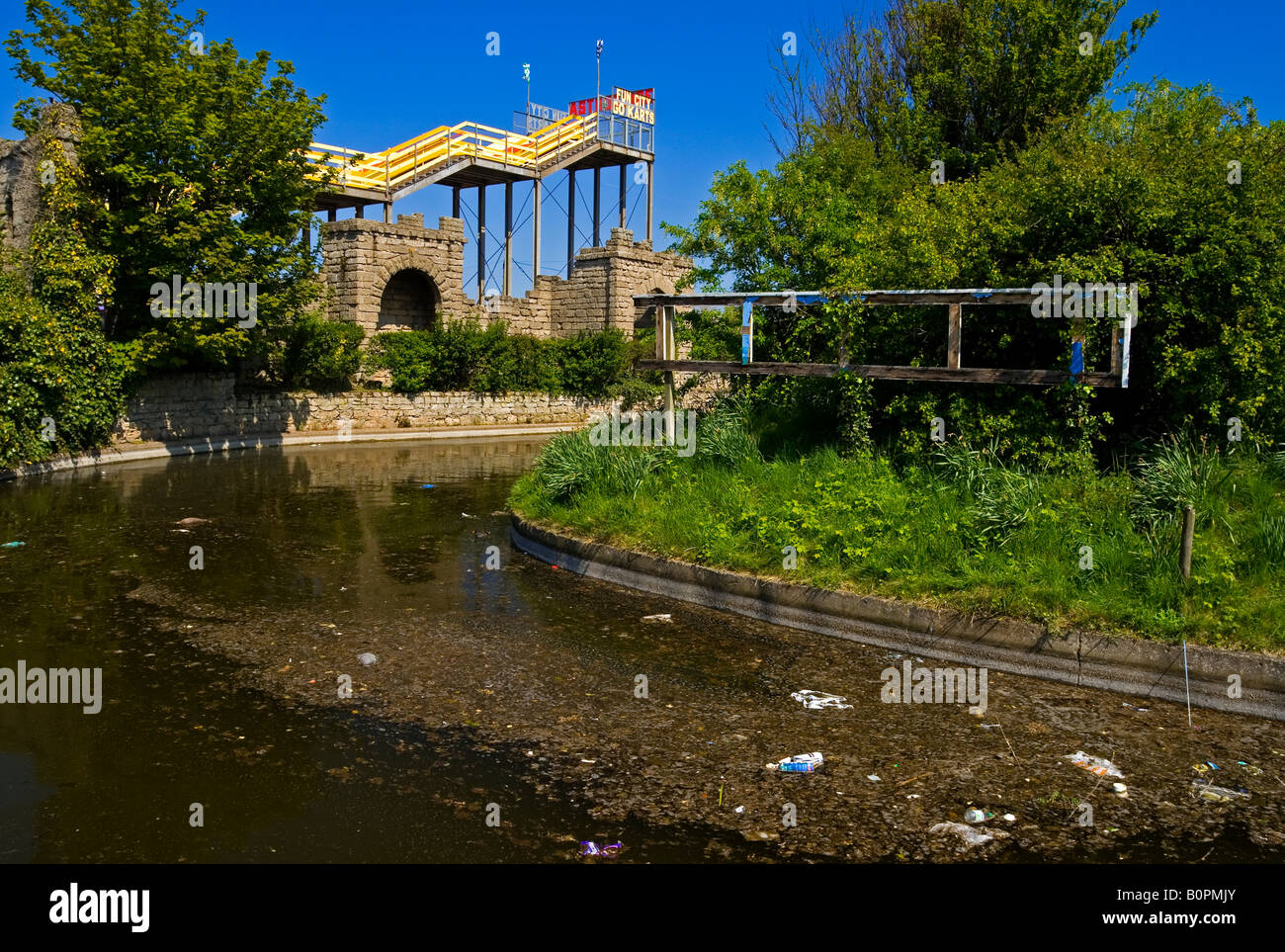 Polluted stream with rubbish and debris floating in the water next to ...