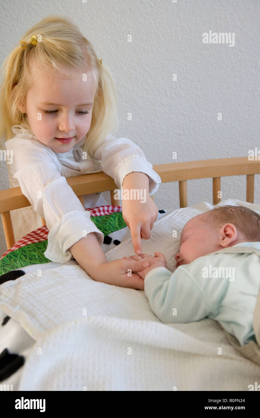 Little girl is touching the new baby Stock Photo - Alamy
