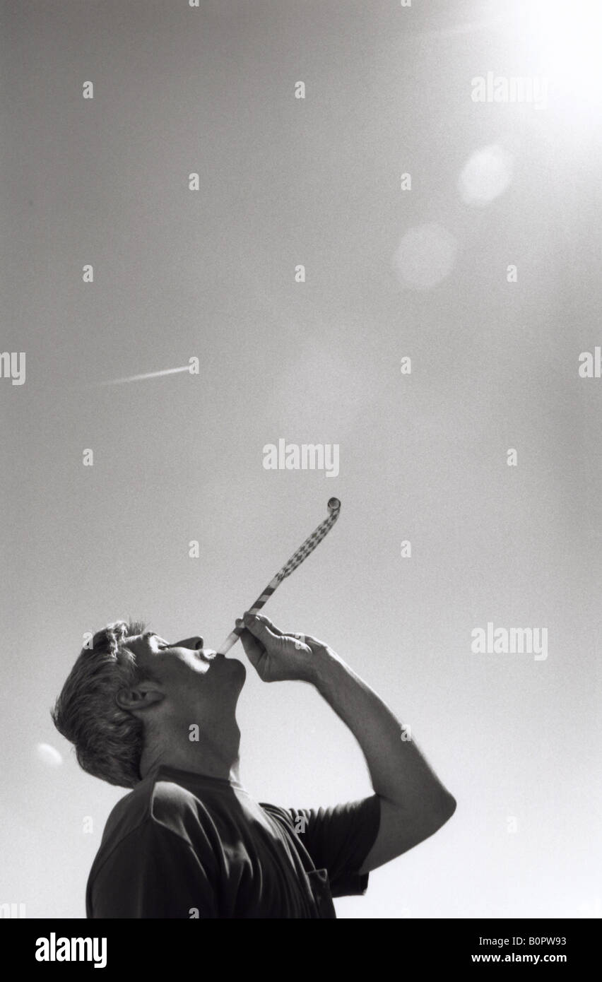 Man blow party horn streamer sun behind backlit hi-res stock ...
