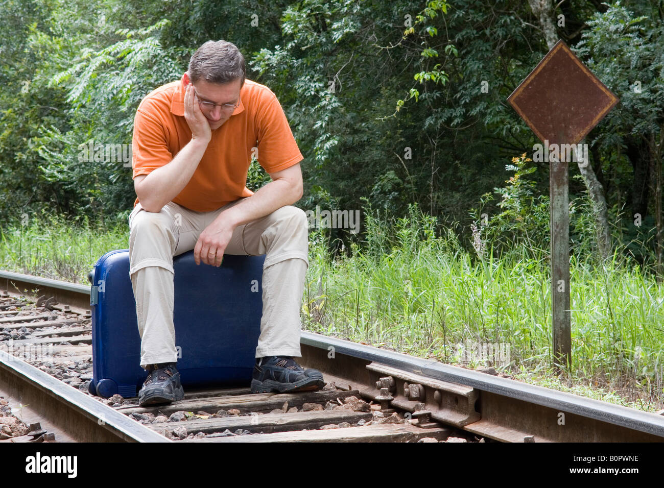 Tired man sitting on his suitcase on a railway Stock Photo - Alamy