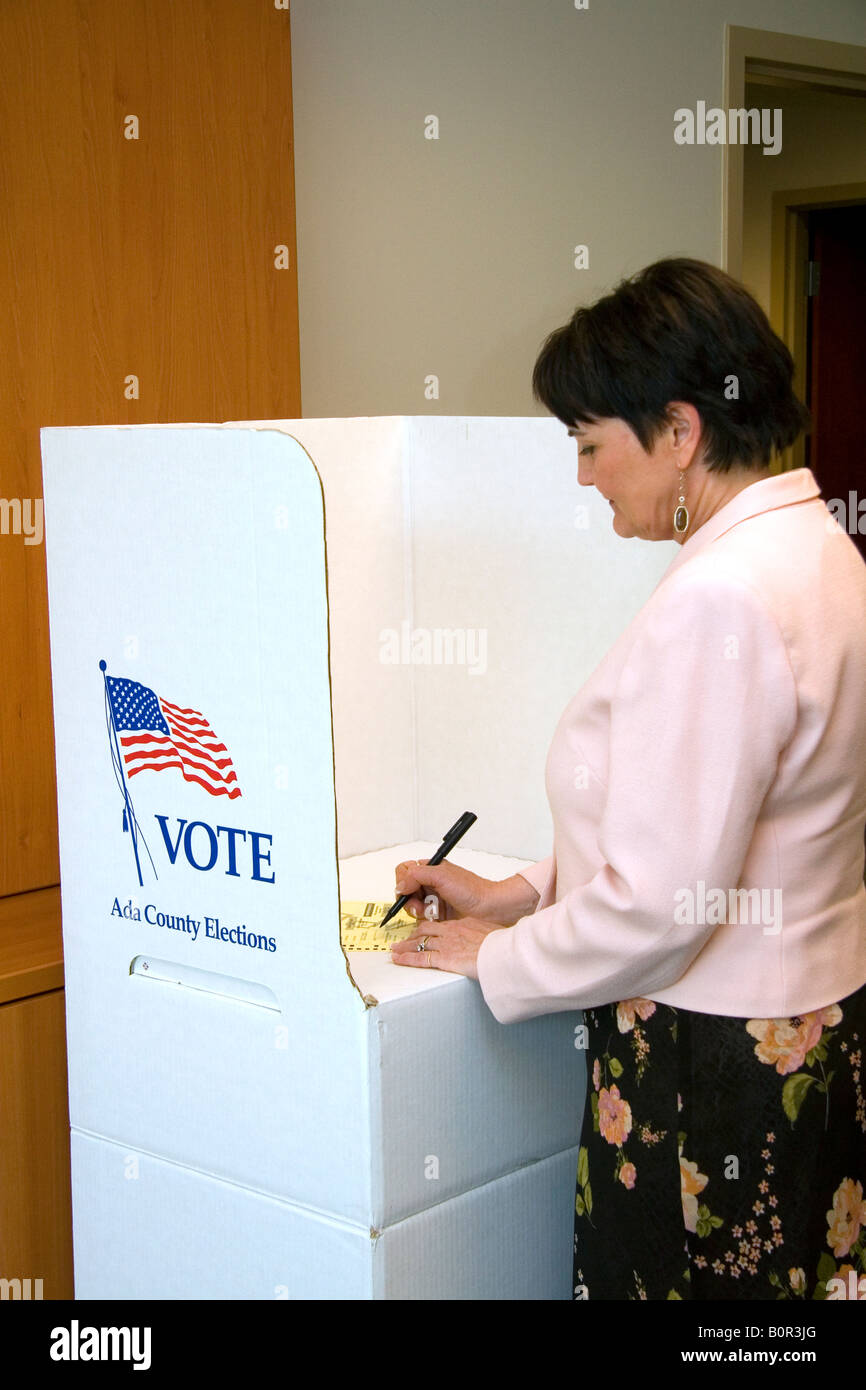 Woman voting on a paper ballot in a cardboard voting booth in Boise ...