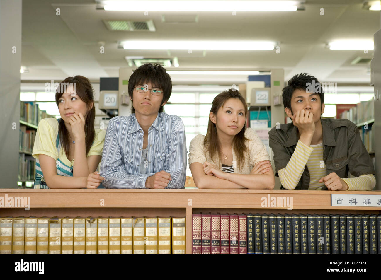 Four students leaning on counter Stock Photo - Alamy
