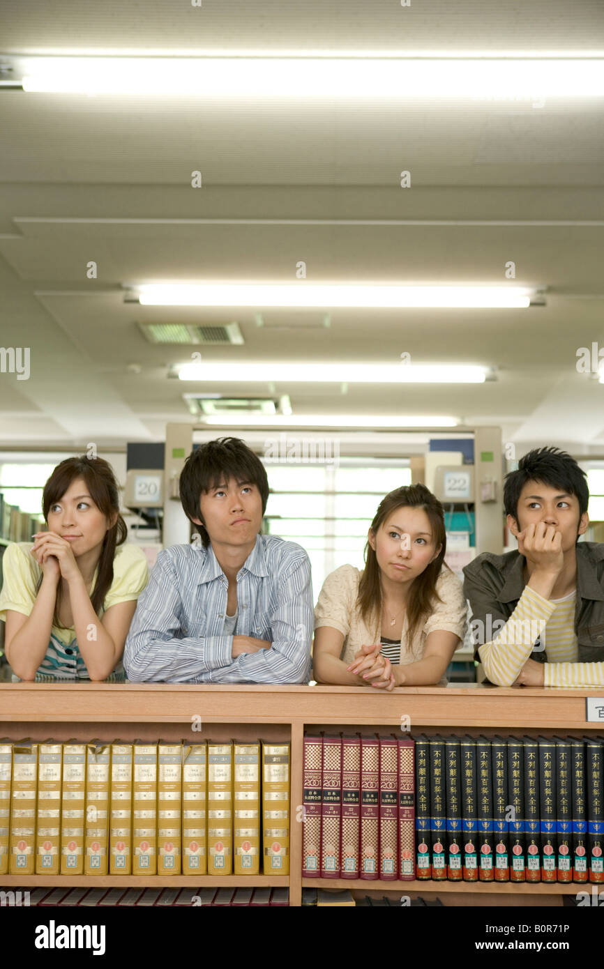 Four students leaning on counter Stock Photo - Alamy