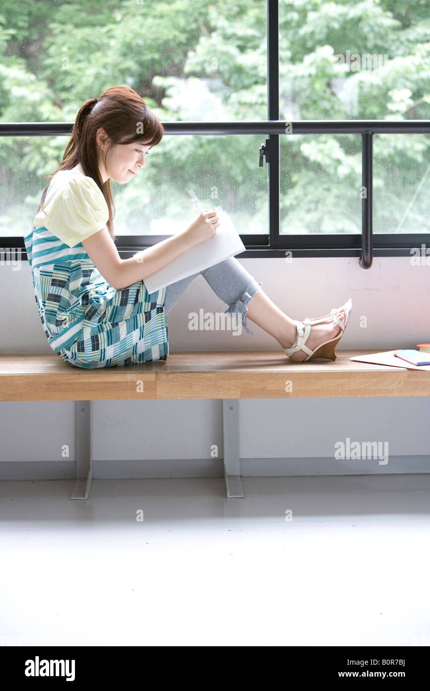 Young woman reading by window Stock Photo - Alamy