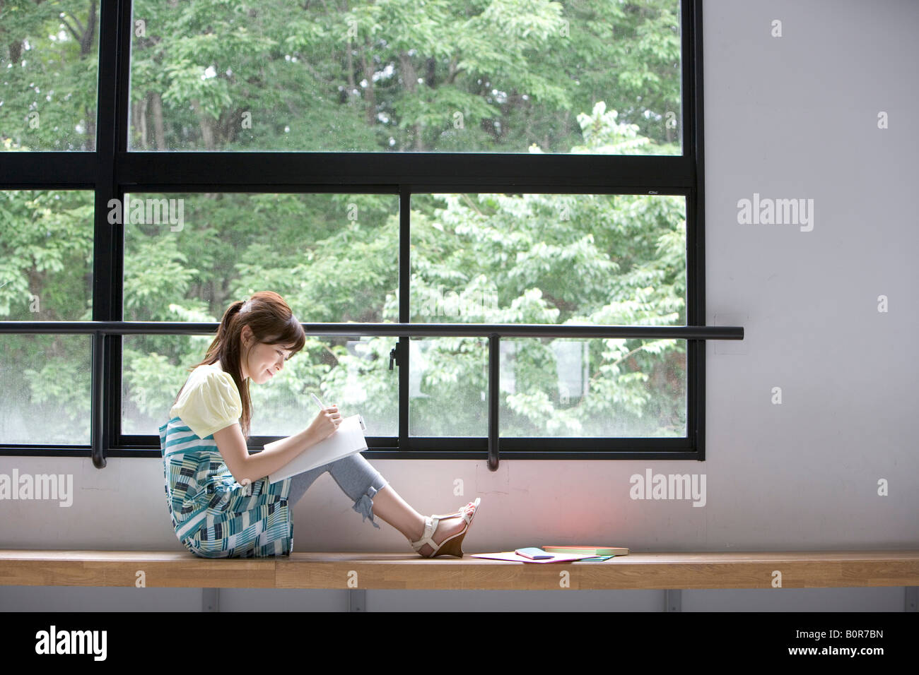 Young woman reading by window Stock Photo - Alamy