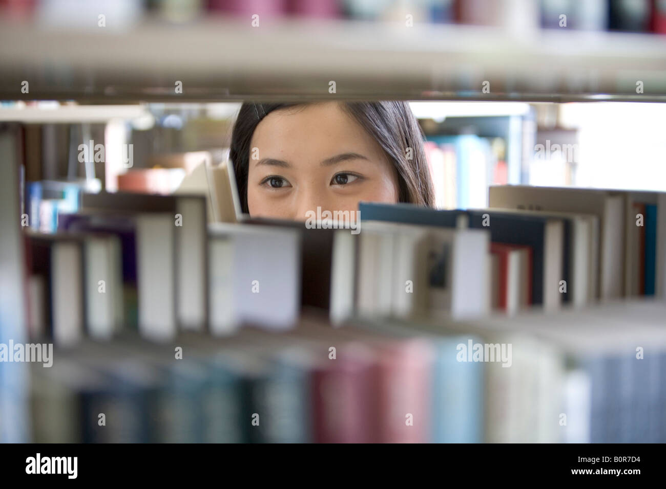 Young woman in library, view behind bookshelf Stock Photo - Alamy