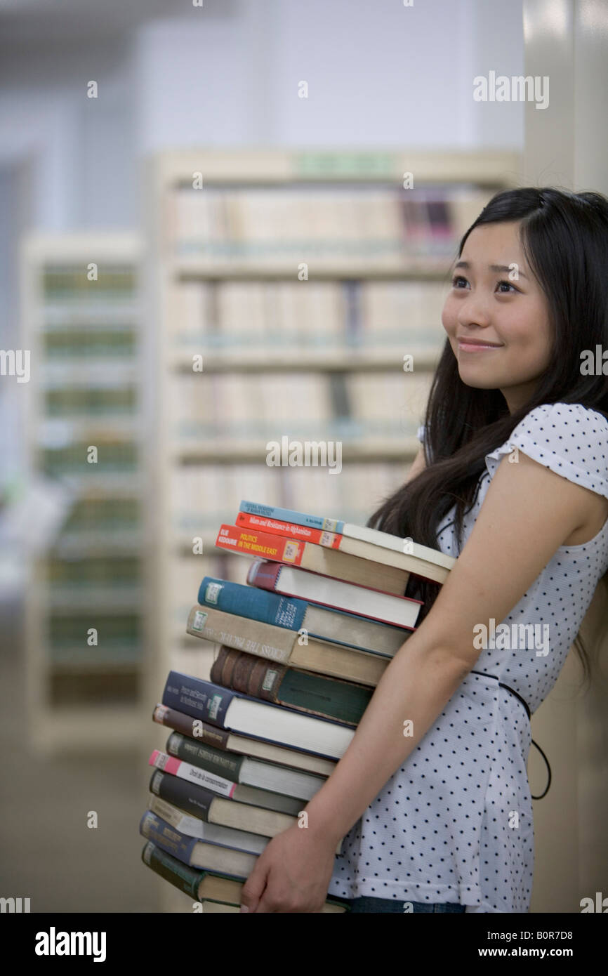 Young woman in library holding stack of books Stock Photo - Alamy