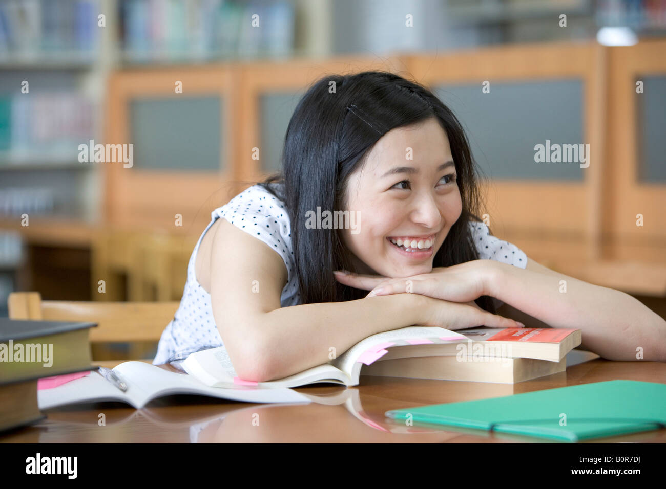 Young woman sitting in library, resting Stock Photo - Alamy