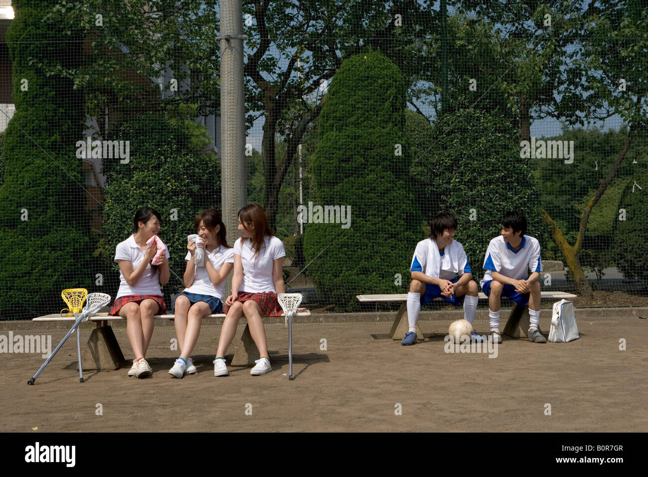 Three girls and two boys sitting on benches during physical education ...