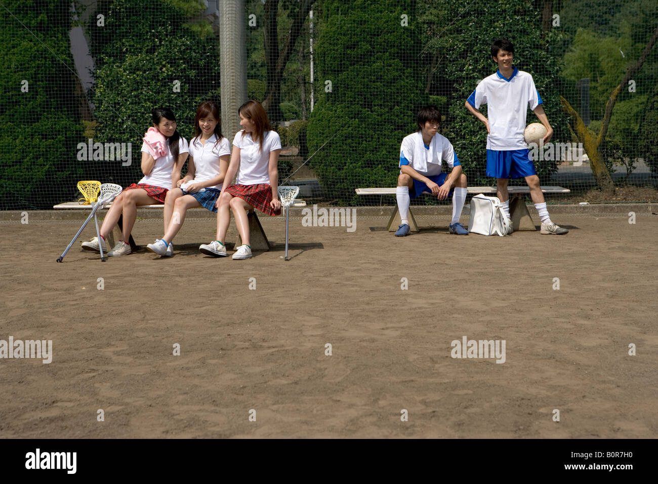 Three girls and two boys sitting on benches during physical education ...